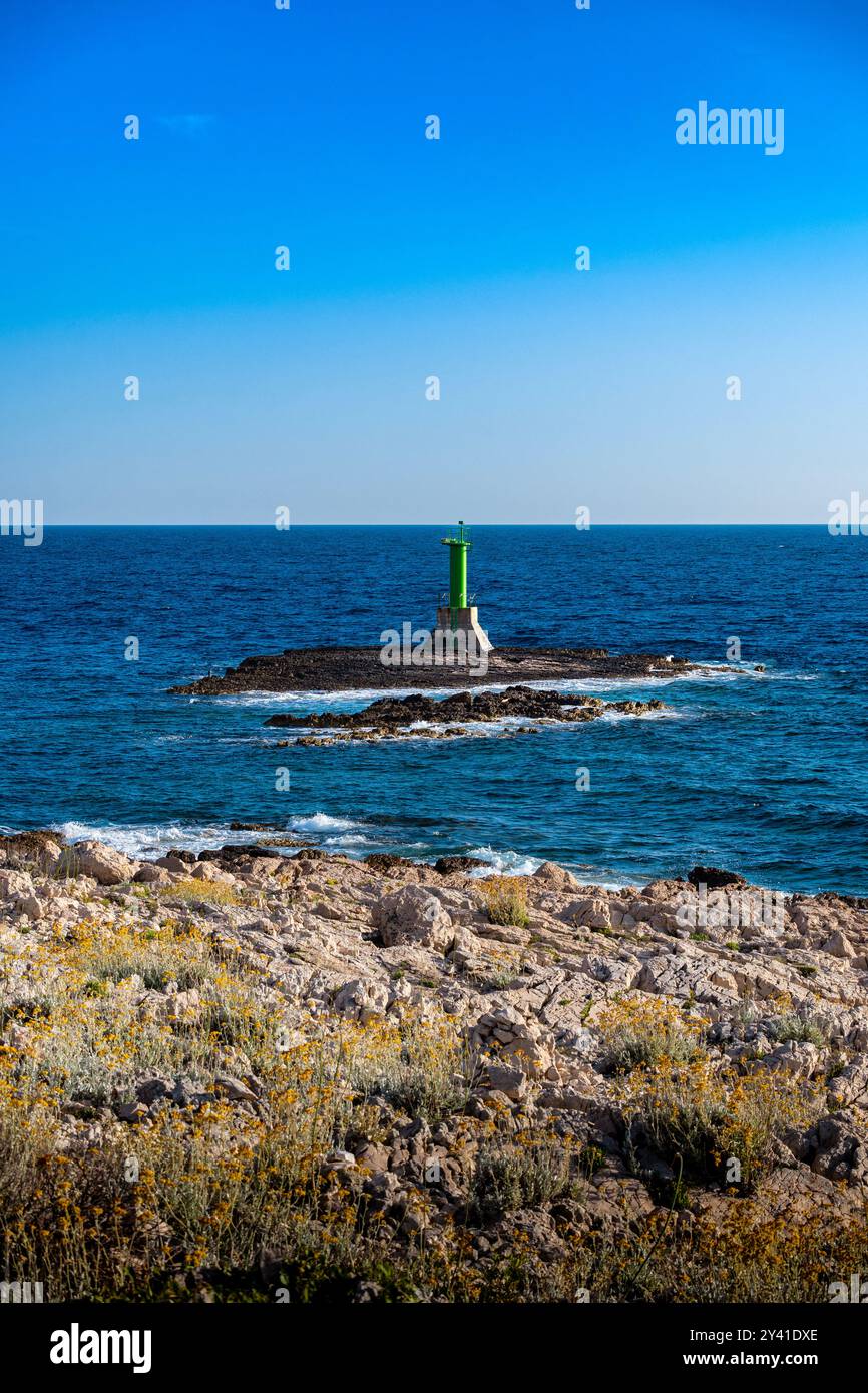 Green lighthouse on the rock in front of Punta Planka cape on the most ...