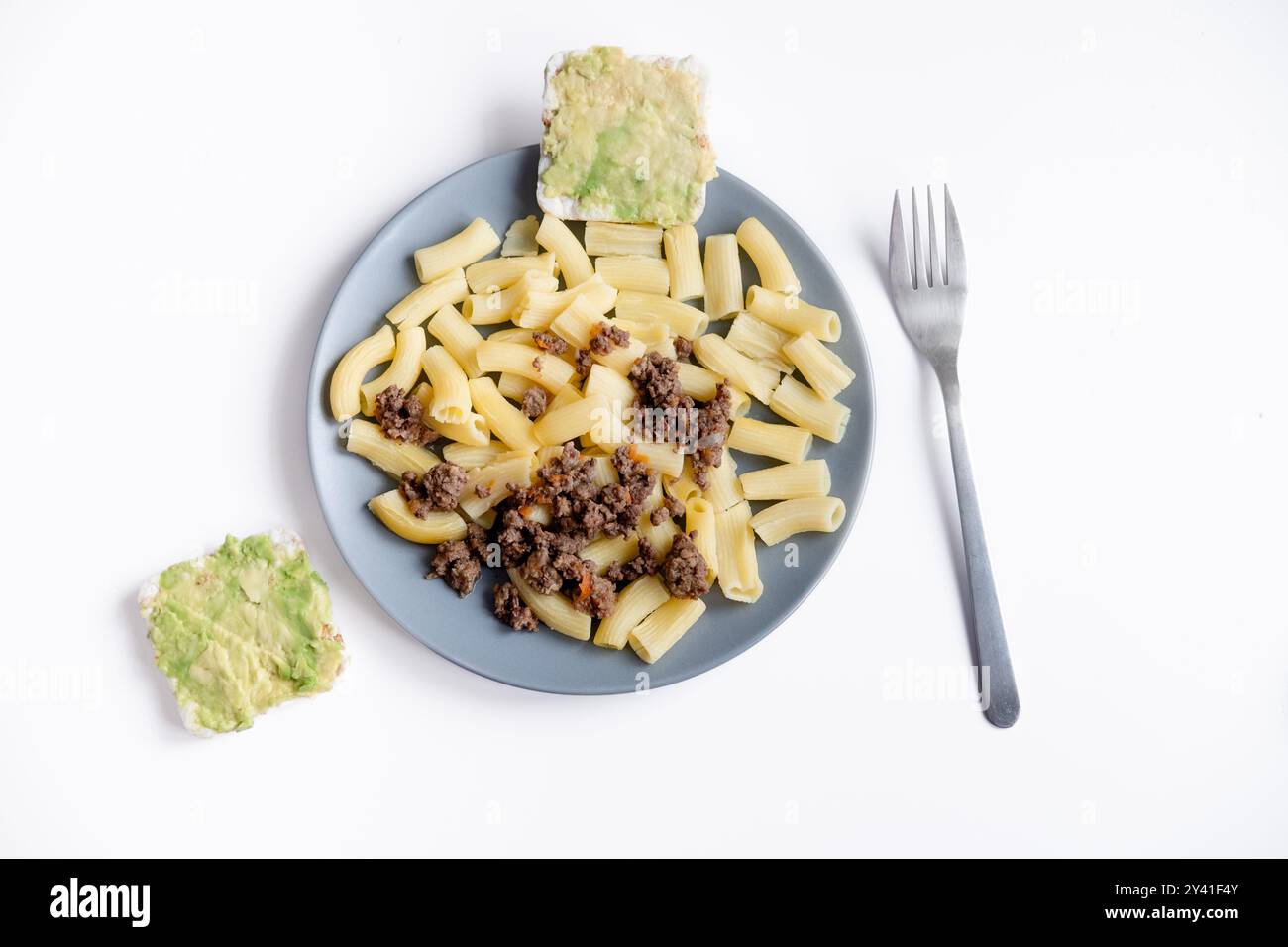 Navy pasta with minced beef and avocado toast on a gray plate, top view ...
