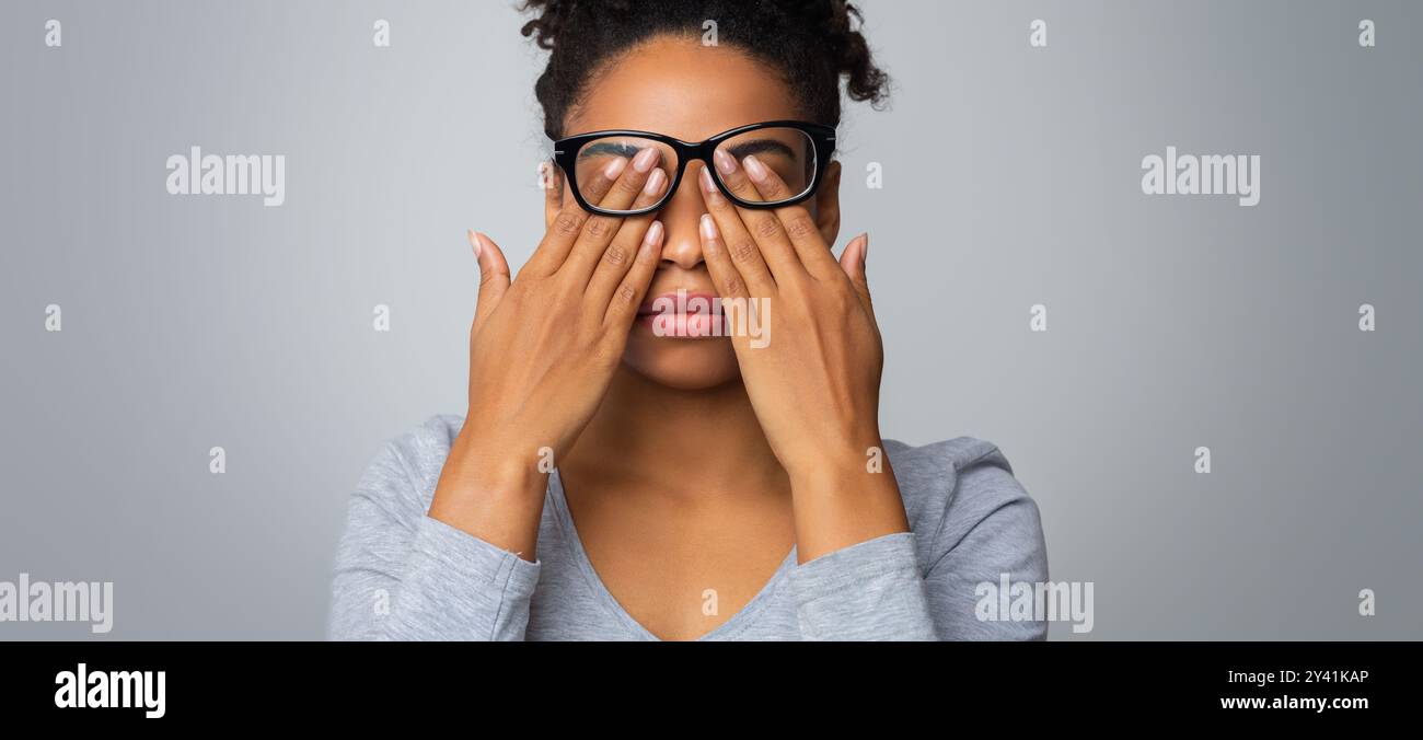 Black girl in glasses rubs eyes, suffering from tired eyes Stock Photo ...