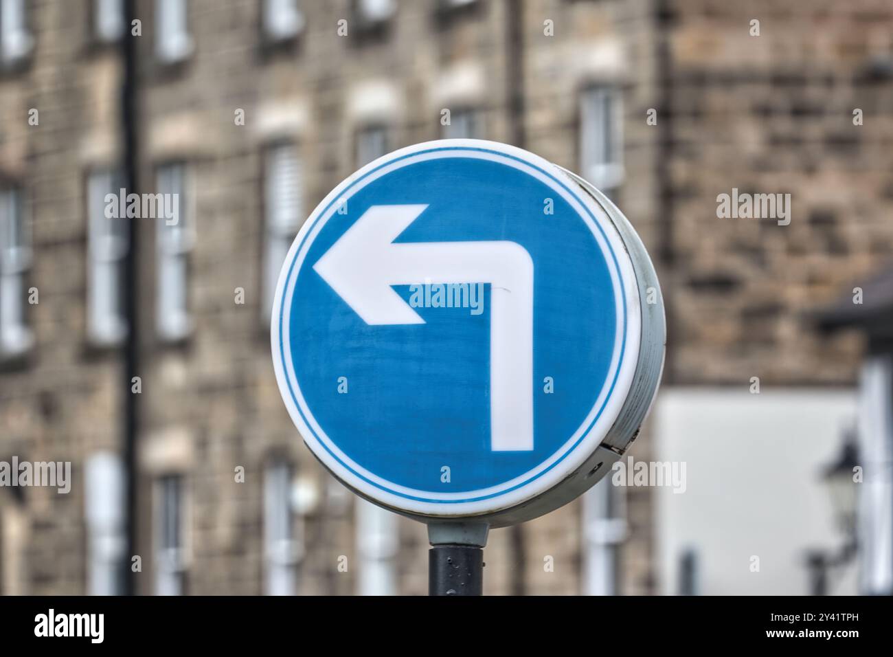 A blue circular traffic sign indicating a left turn, with a white arrow ...