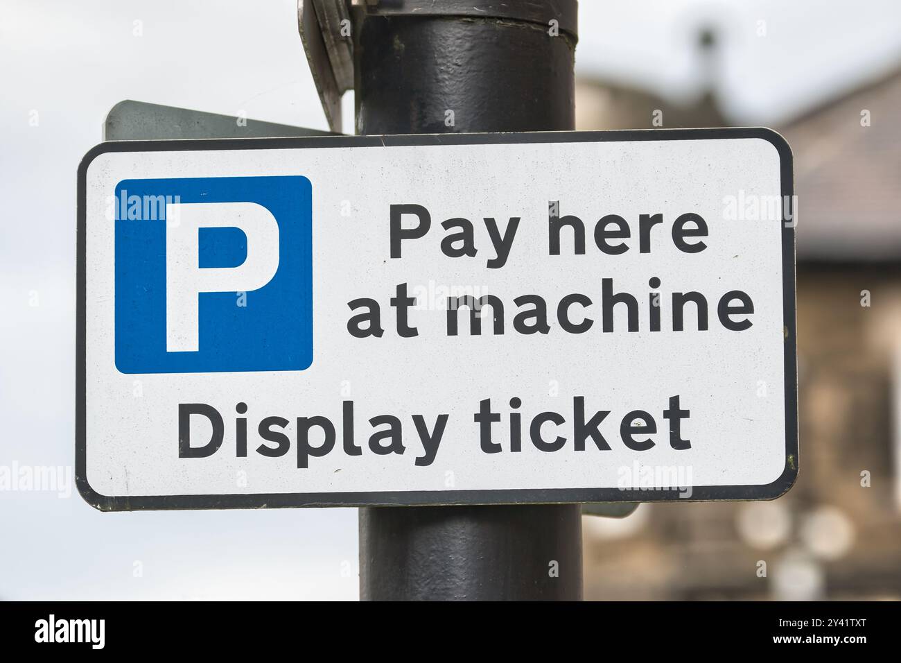 A parking sign indicating payment instructions. It reads 'Pay here at ...