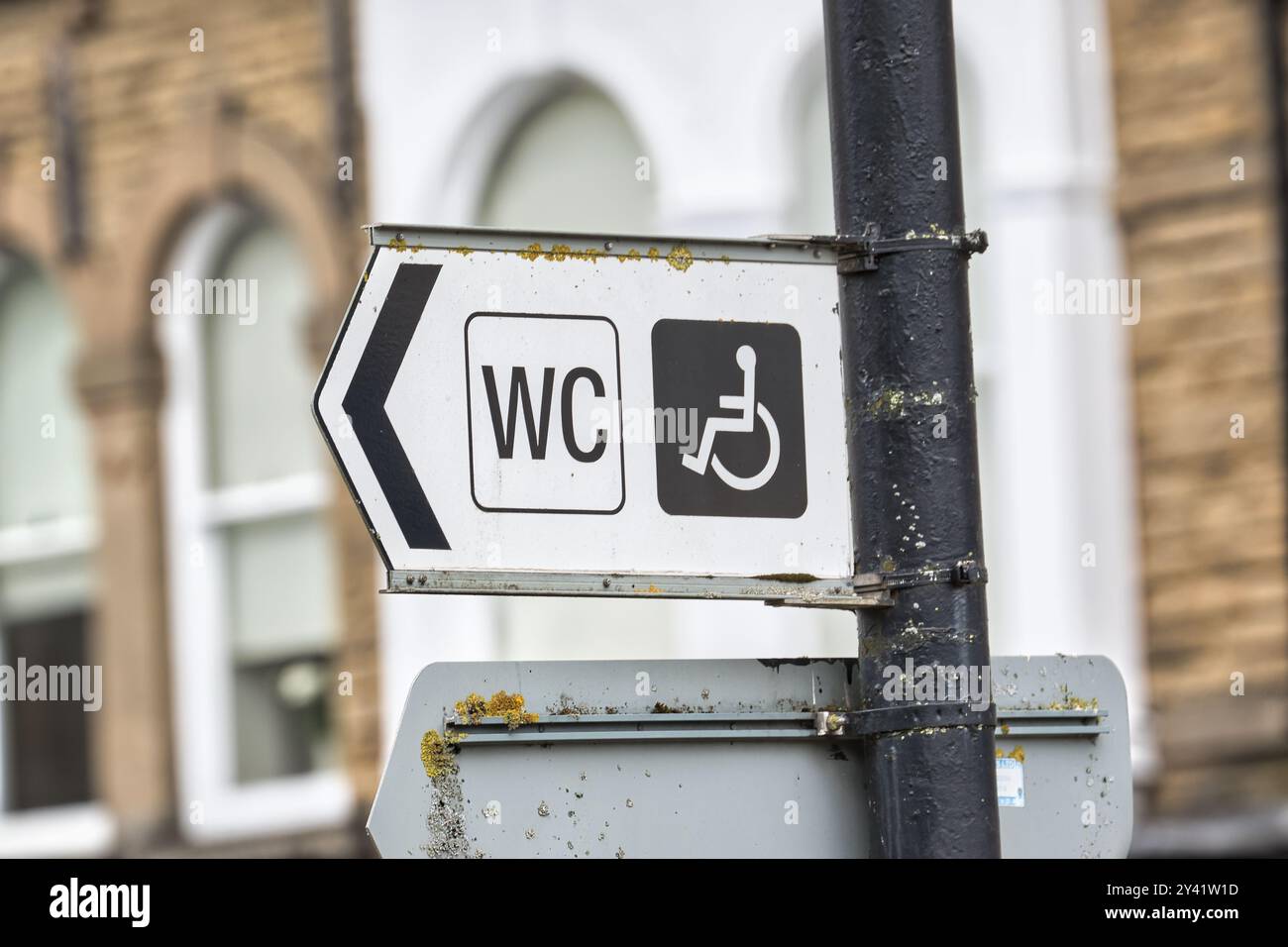 A street sign indicating the direction to a restroom (WC) with a ...