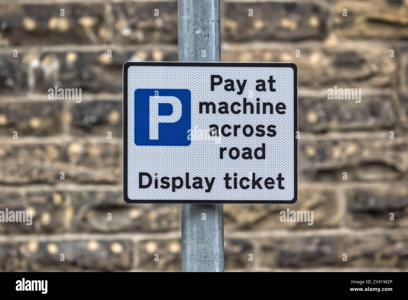 A parking sign instructing drivers to pay at a machine across the road ...
