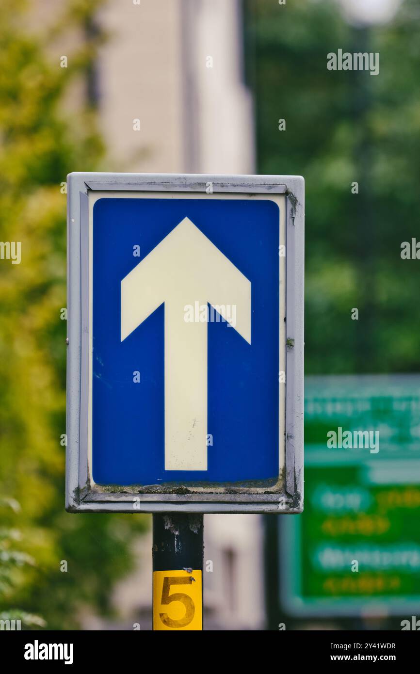 A blue road sign with a large white arrow pointing upwards, indicating ...