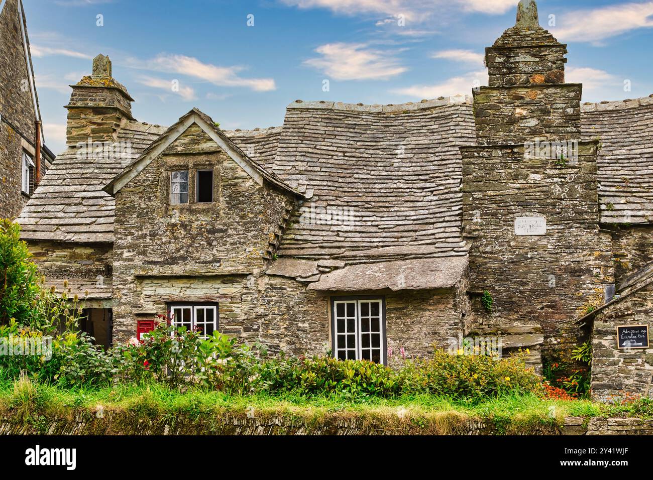 A charming old stone cottage with a unique slate roof, surrounded by ...