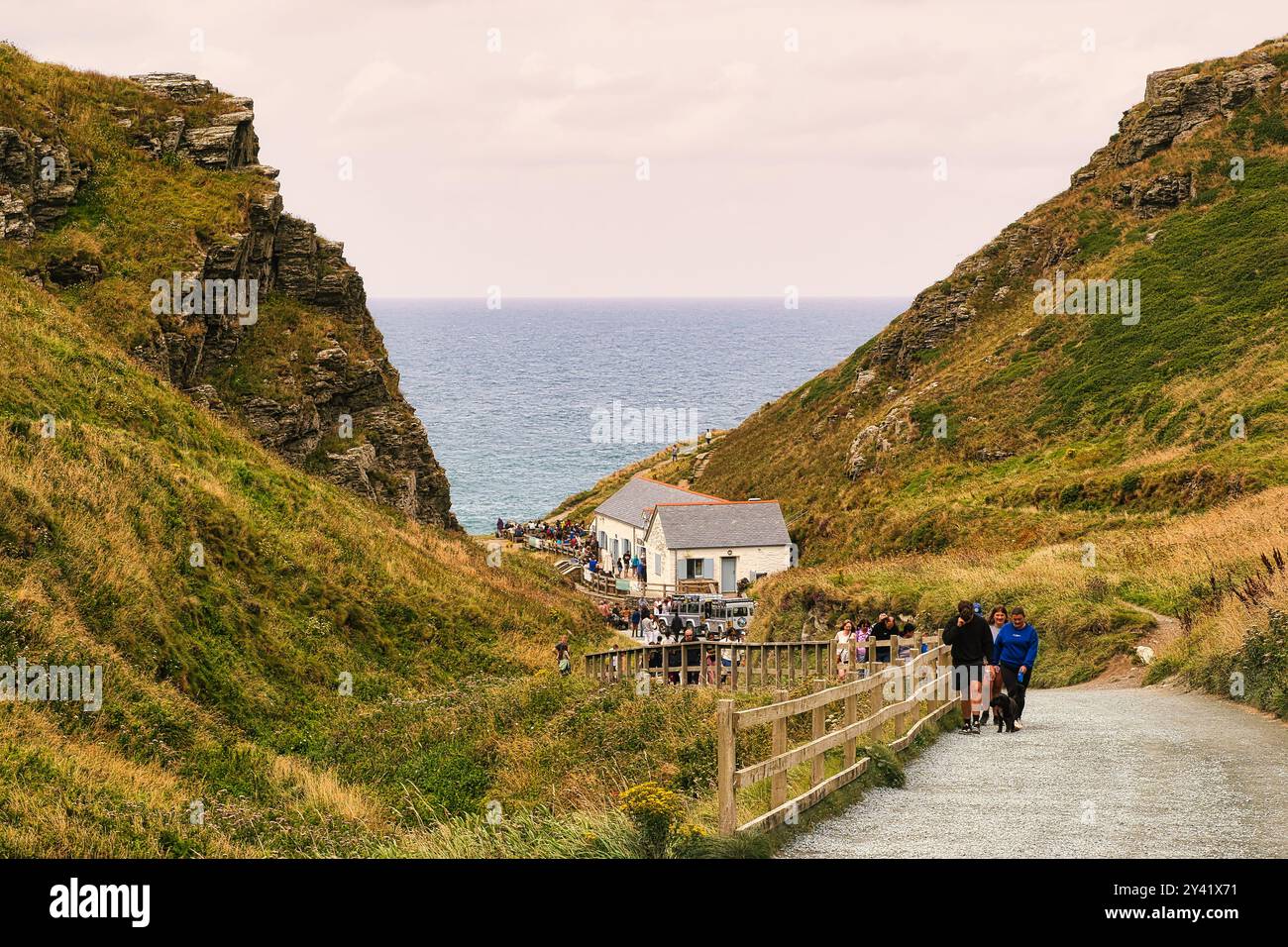 A scenic coastal pathway leading to a beach, flanked by steep cliffs ...
