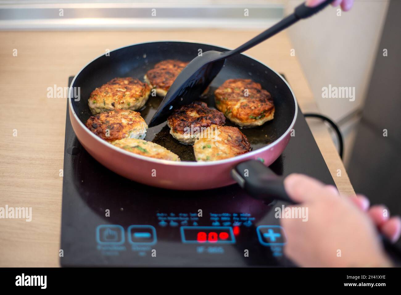 Cooking. The frying pan is on the induction stove, the hostess is ...