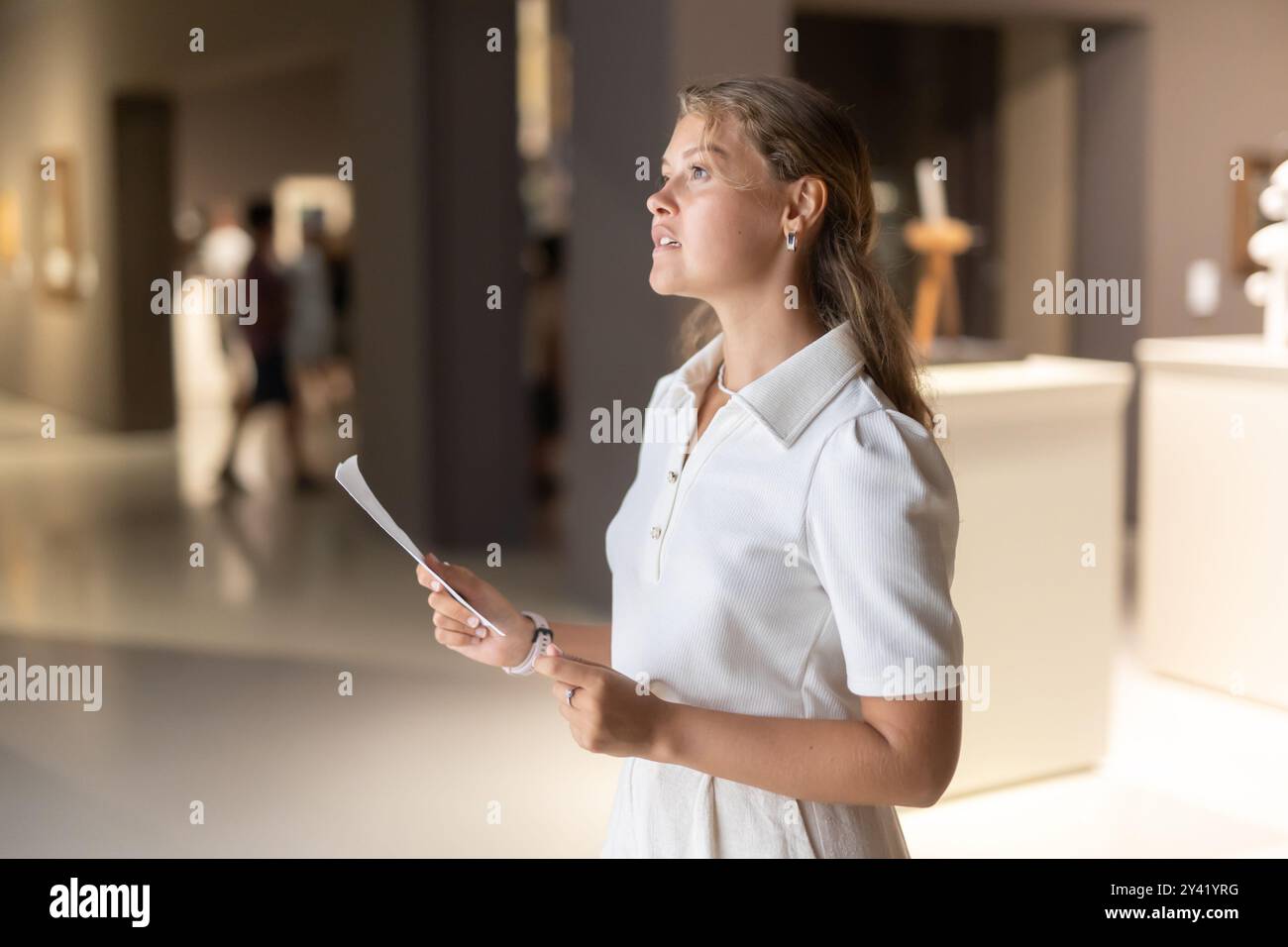 Woman with sheet piece of paper in hands view sculpture in museum hall ...
