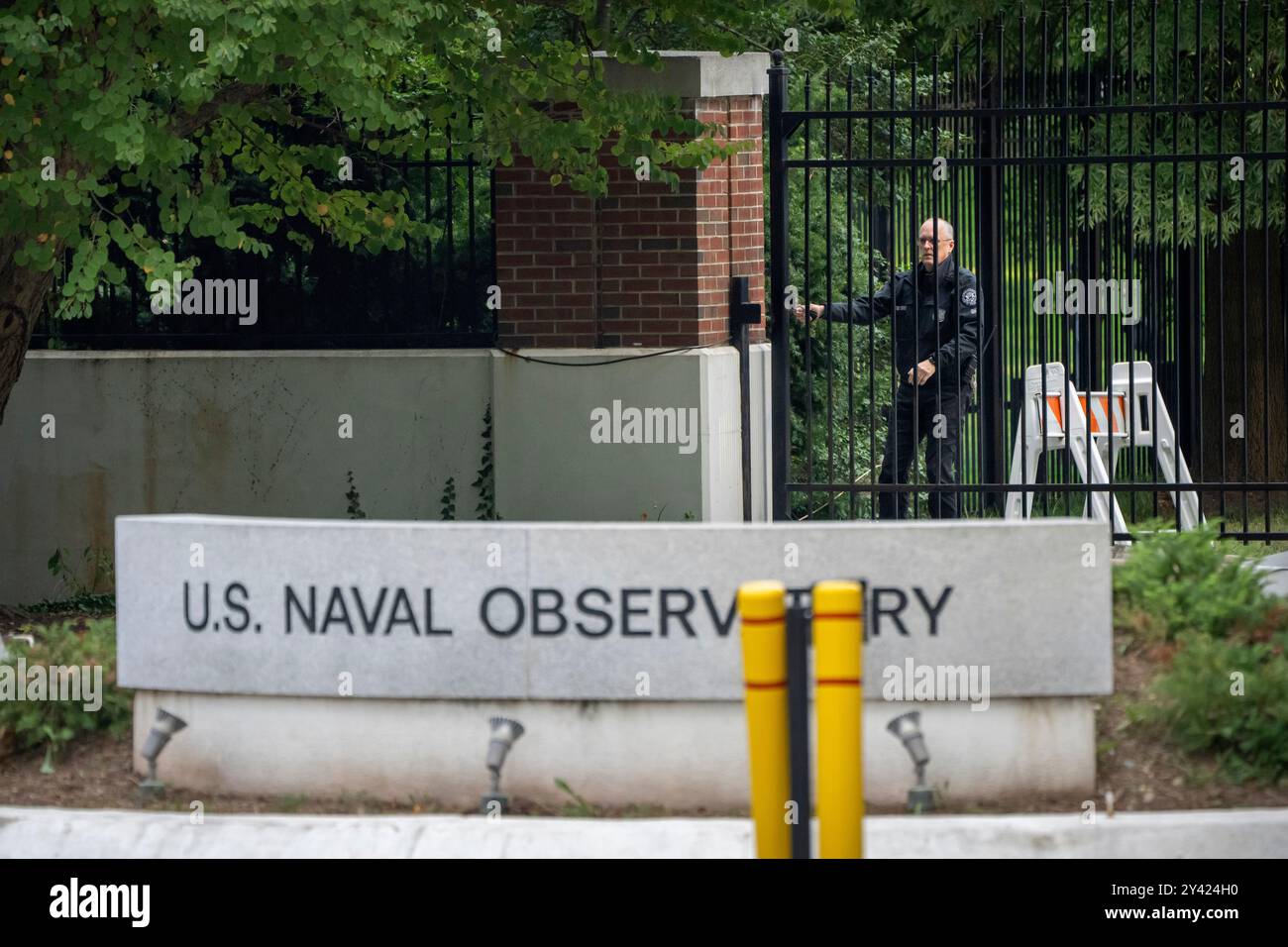A security officer opens a gate for a vehicle to leave the U.S. Naval ...