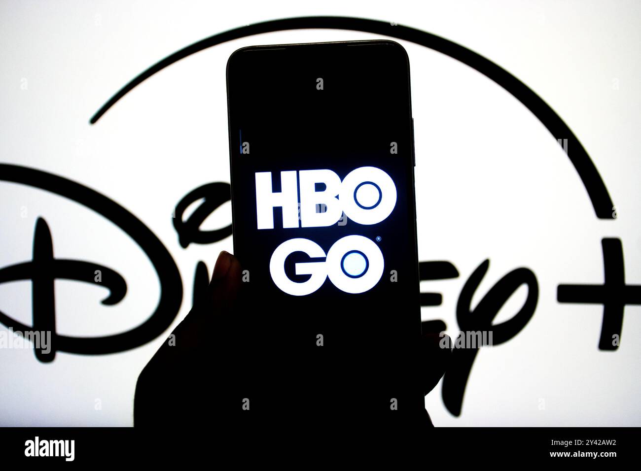 In this photo illustration, a HBO GO logo seen displayed on a smartphone with a Disney Plus Logo ...