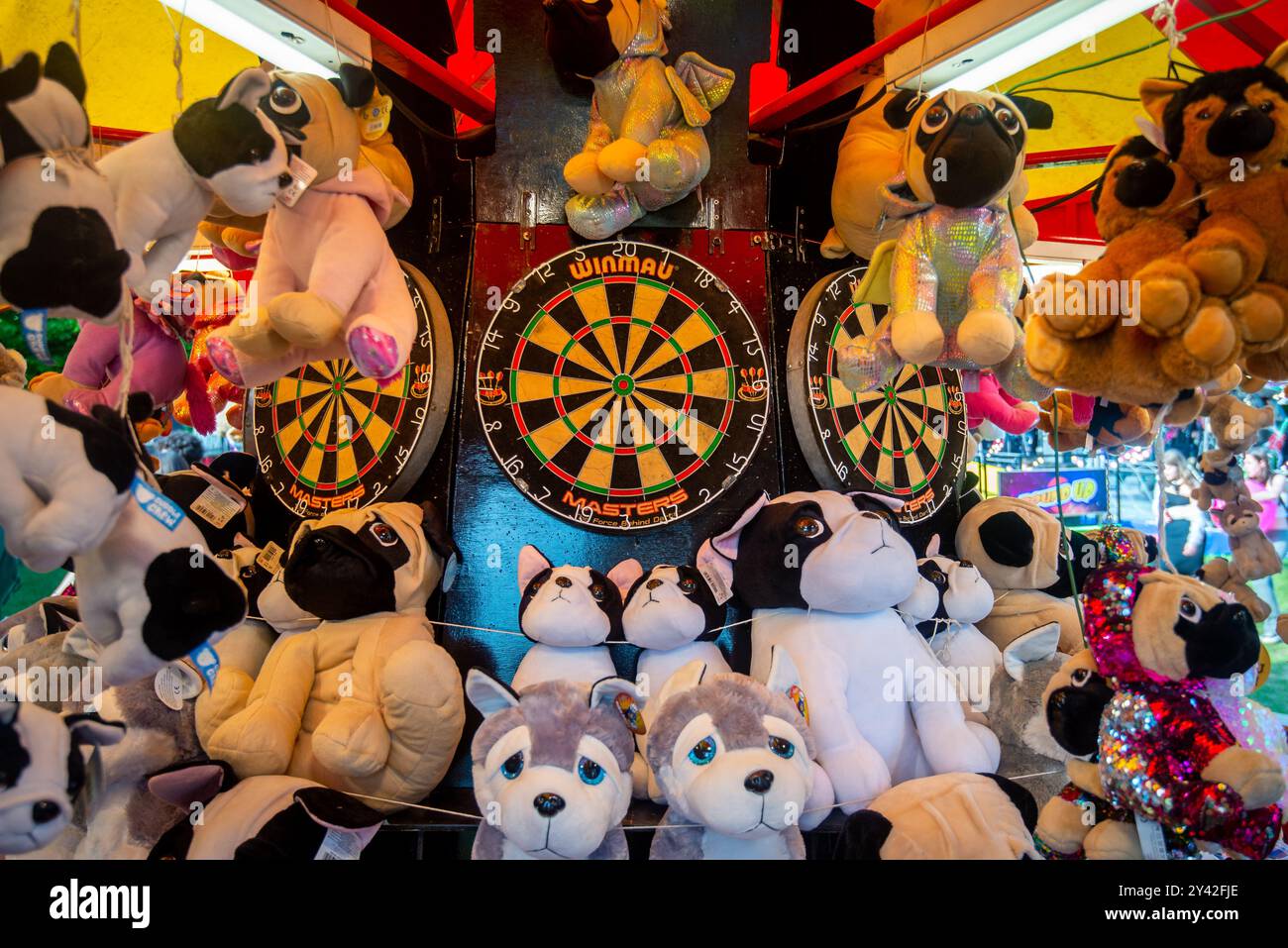 Close up of stuffed animal toy prizes and dartboard at British funfair ...