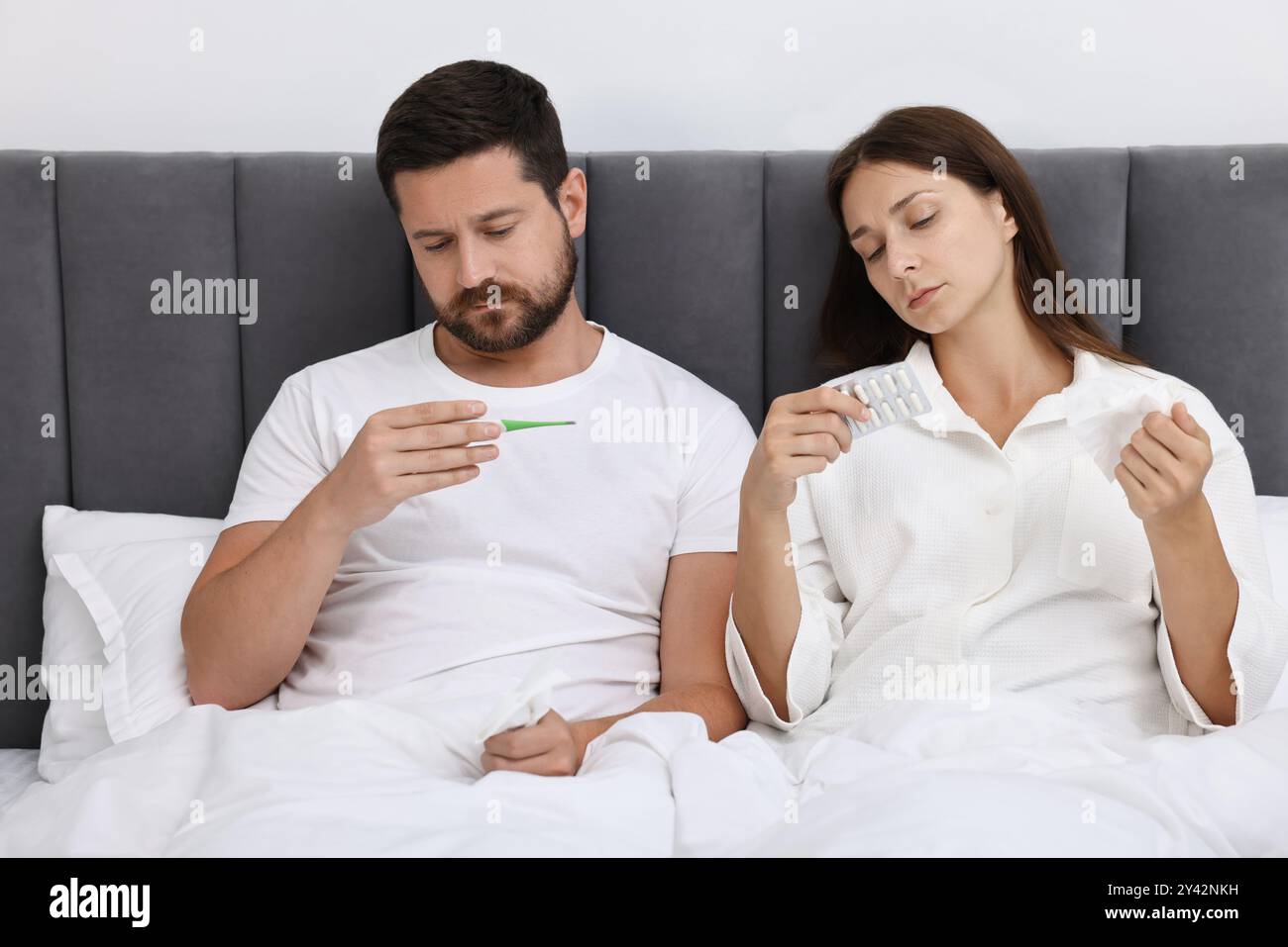 Cold symptom. Couple suffering from fever in bed at home Stock Photo ...