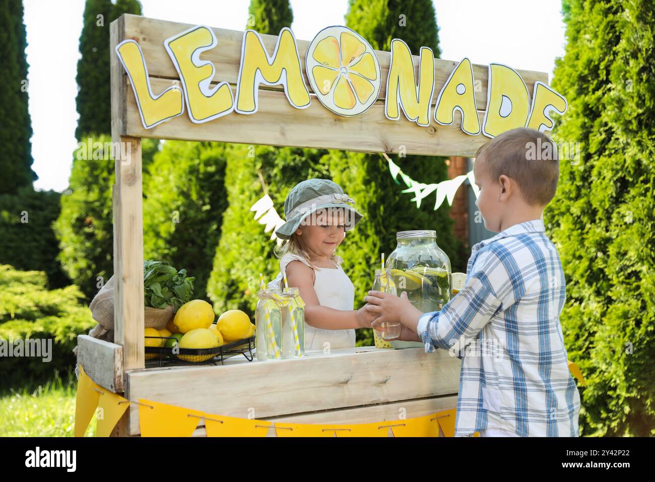 Cute little girl selling natural lemonade to boy in park Stock Photo ...