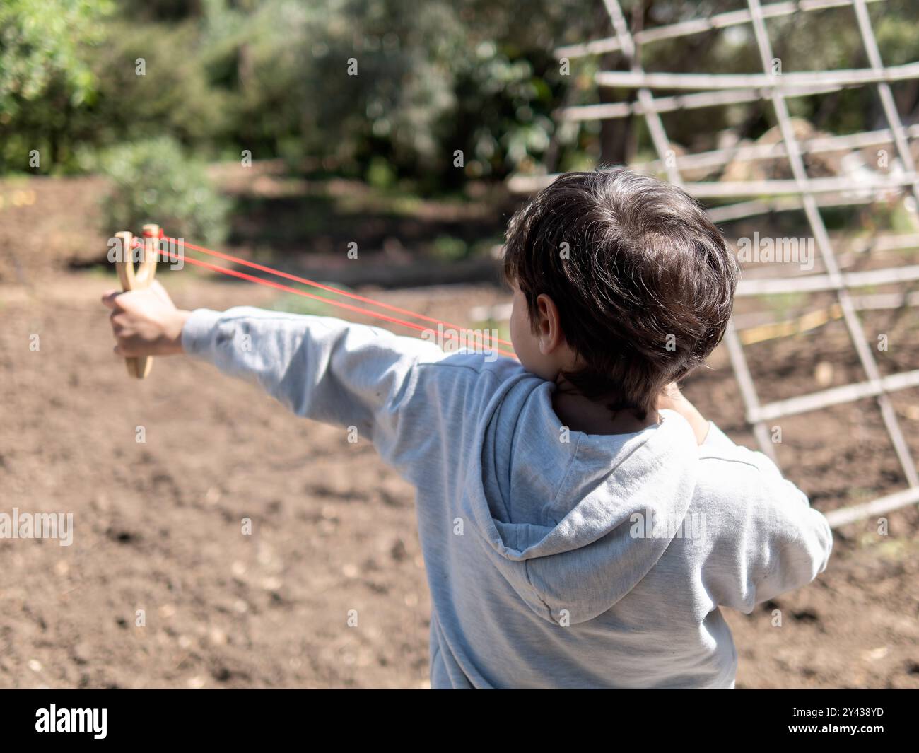 Boy aiming a slingshot in a sunny outdoor environment Stock Photo - Alamy