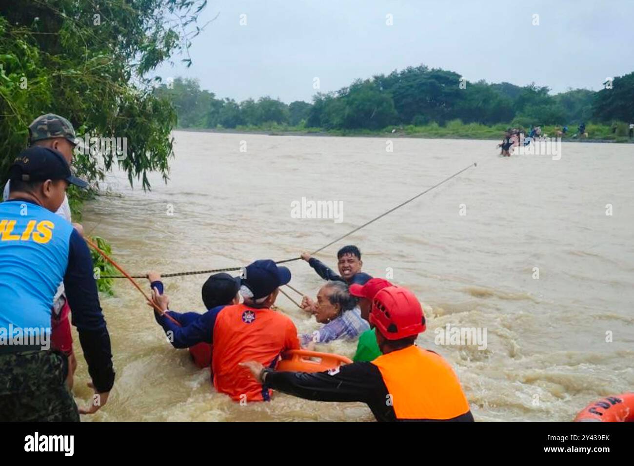 In this handout photo provided by the Philippine Coast Guard, rescuers assist residents as they ...