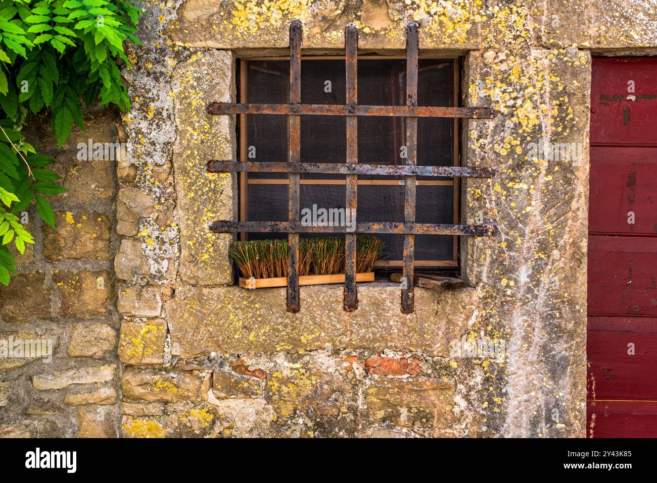 old window with iron grate and broom on the windowsill in a small town ...