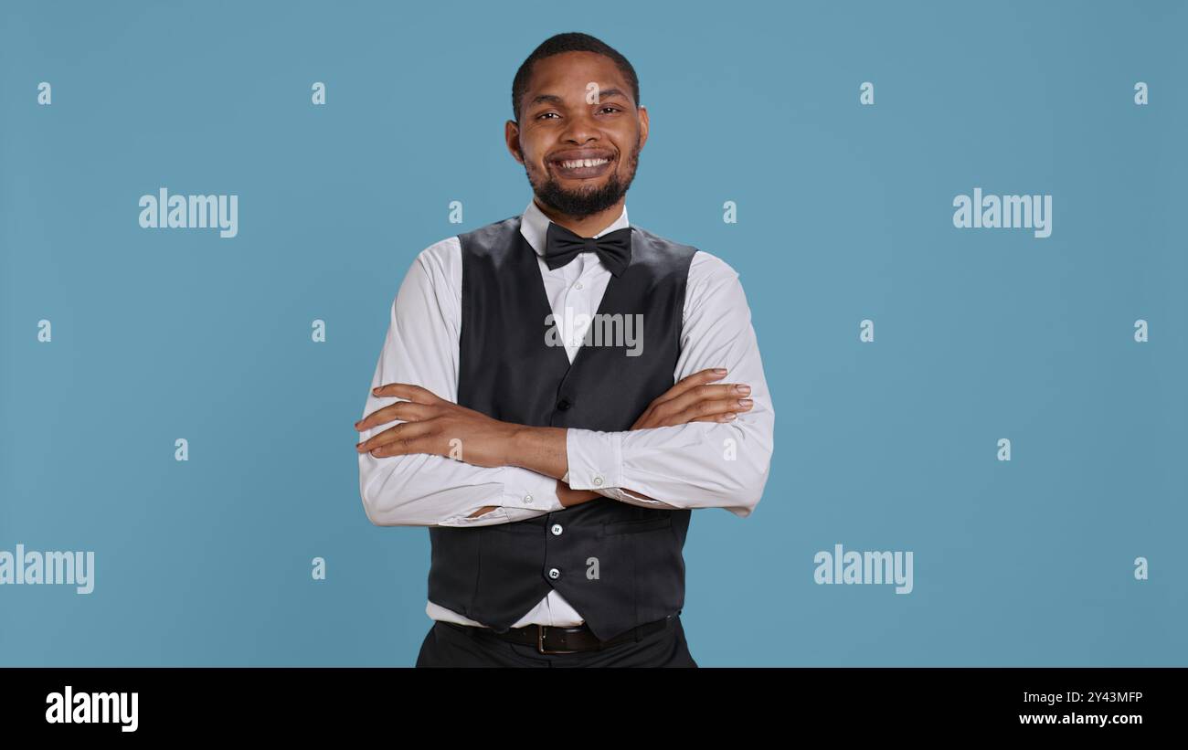 Confident cheerful hotel concierge staff poses with arms crossed in ...