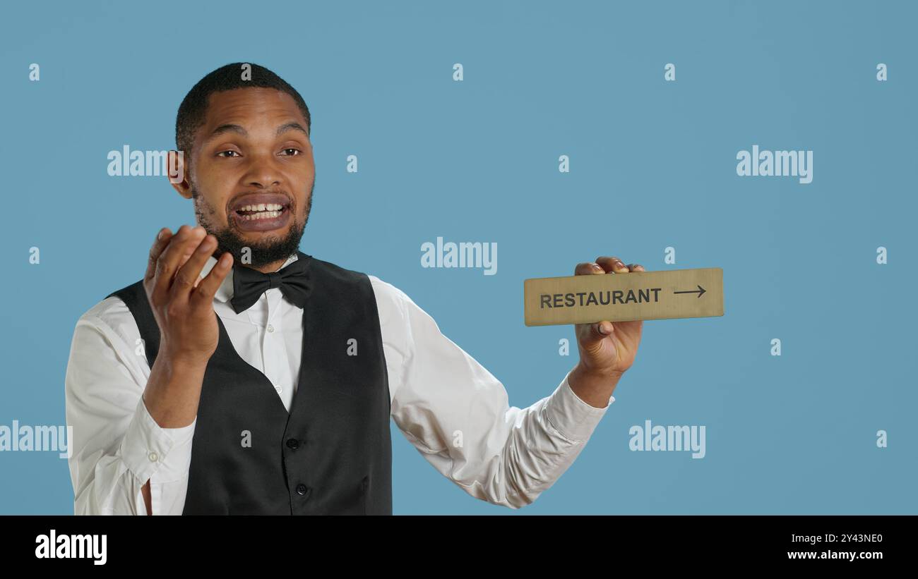 Doorman bellhop showing the restaurant direction with a hotel sign ...