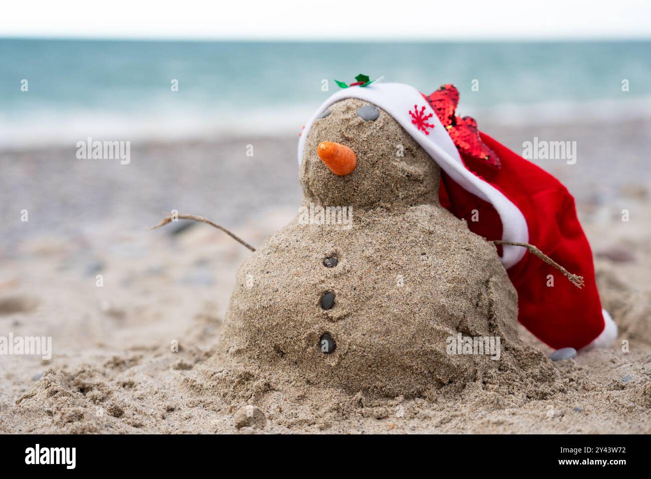 Snowman made with beach sand with a Santa Claus hat on Christmas Day ...