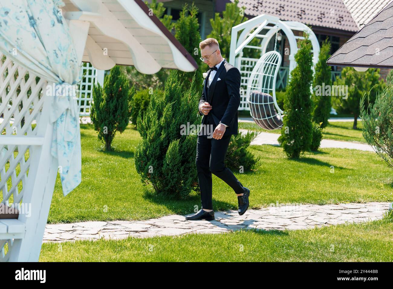 Elegant Man Walking on Garden Path in Sunglasses and Tuxedo at Luxury ...