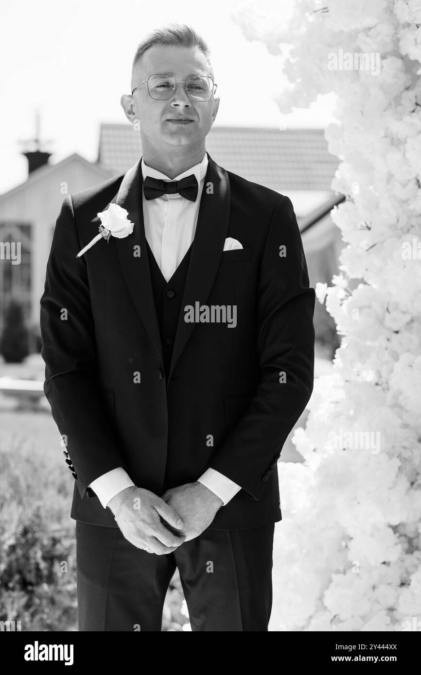 Elegant Groom in Classic Black Tuxedo at Outdoor Wedding Ceremony with ...