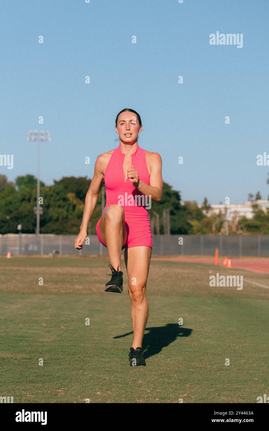 Female track athlete doing drills on grass Stock Photo - Alamy