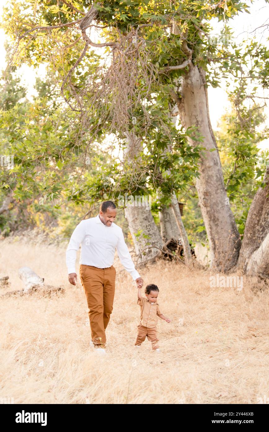 Father and son walking through tall brown grass Stock Photo - Alamy
