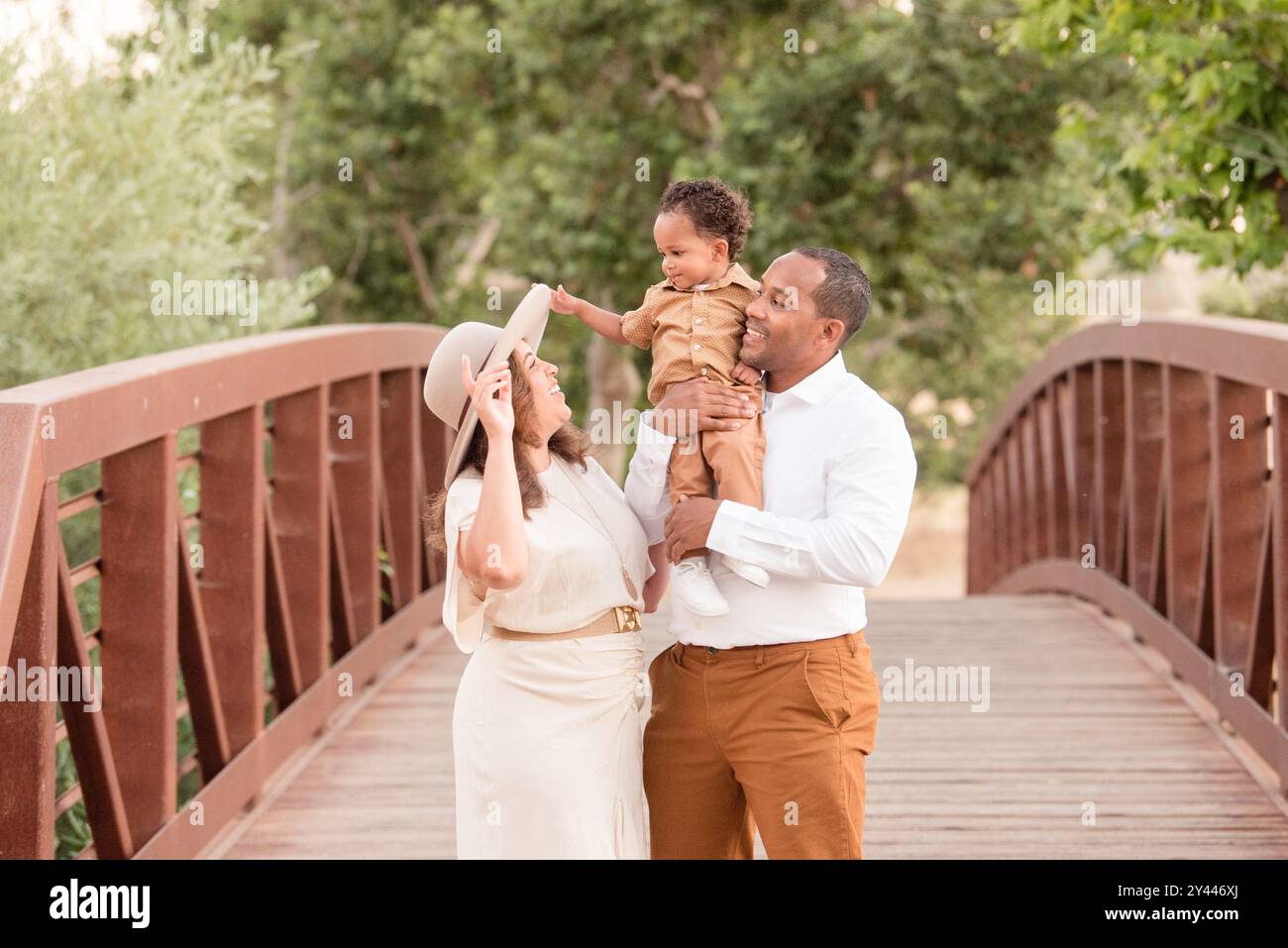 Parents holding son laughing with him on a bridge Stock Photo - Alamy