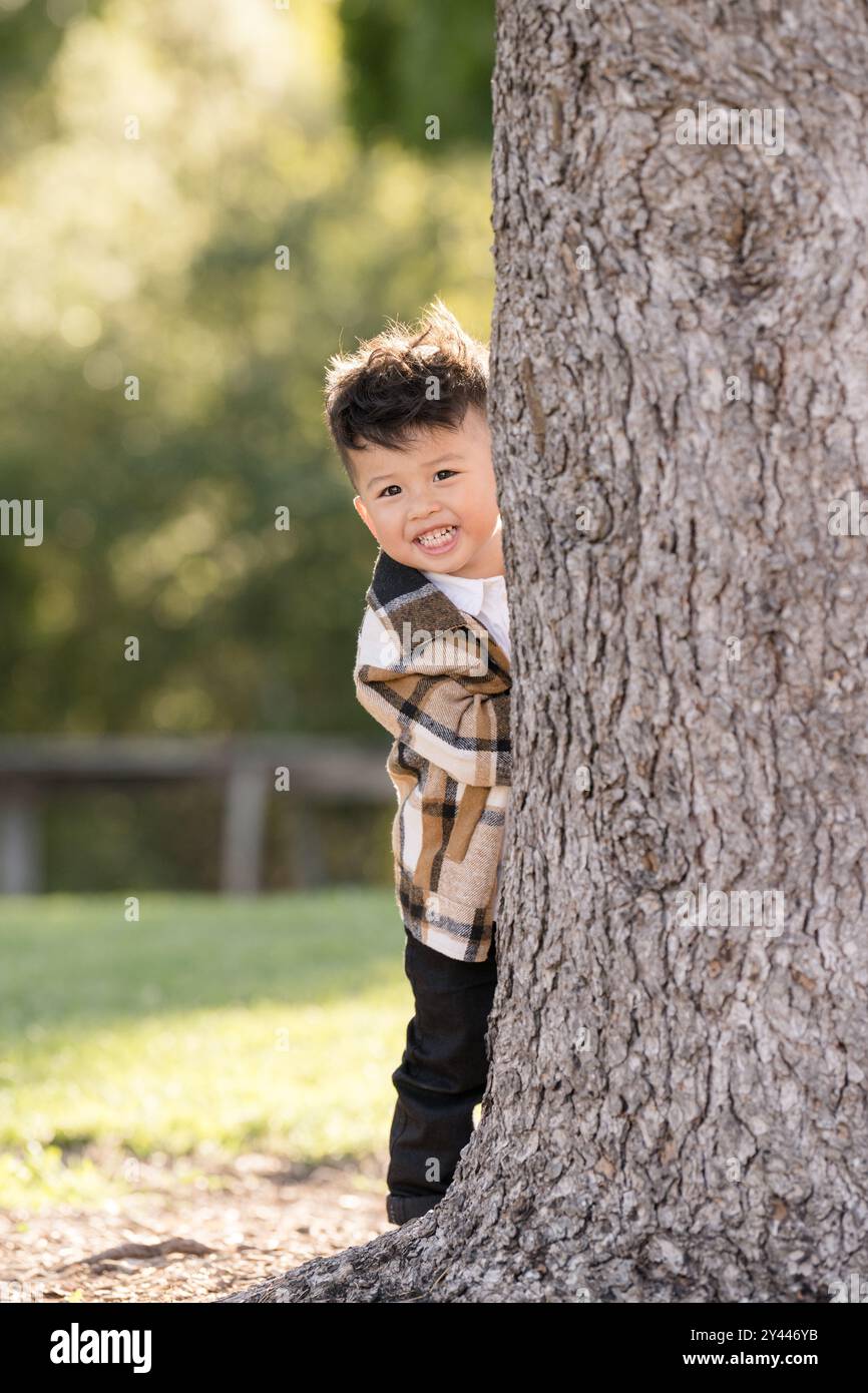 Boy peeking out behind a tree Stock Photo - Alamy