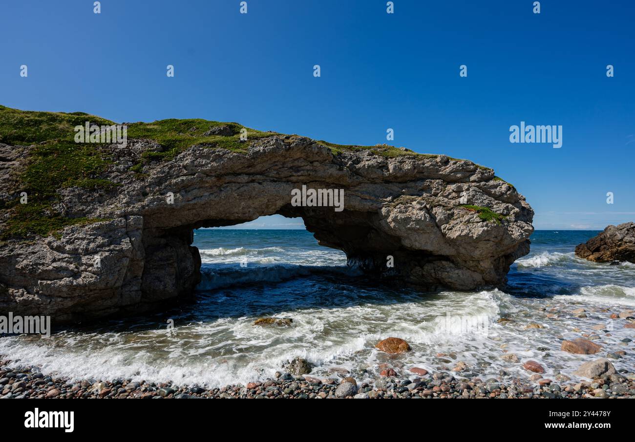 View of natural rock arch on beach in Newfoundland, Canada Stock Photo ...