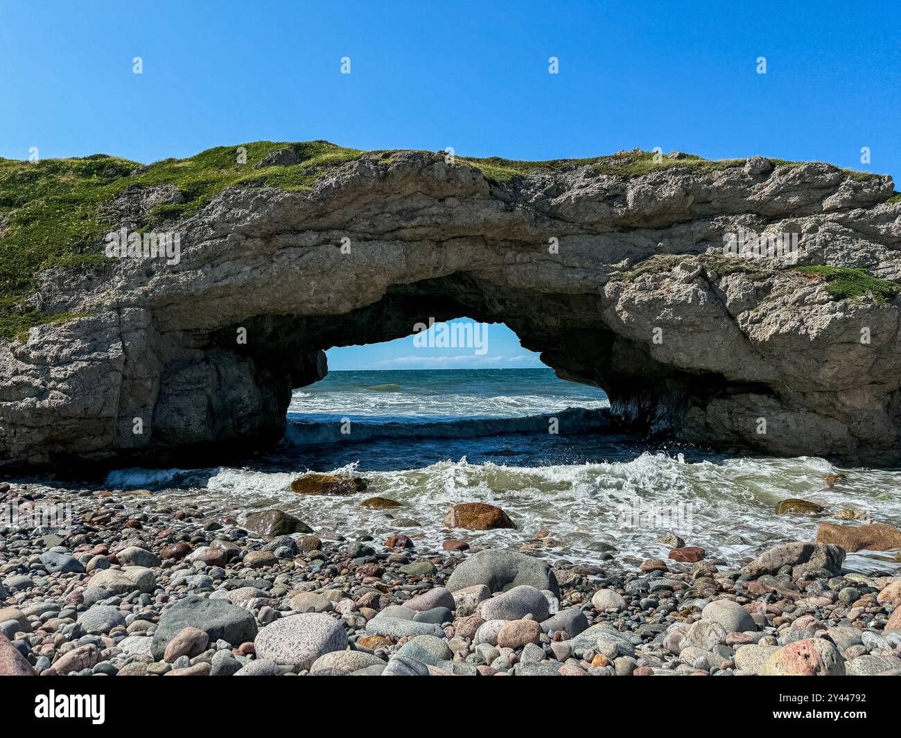 View of natural rock arch on beach in Newfoundland, Canada Stock Photo ...
