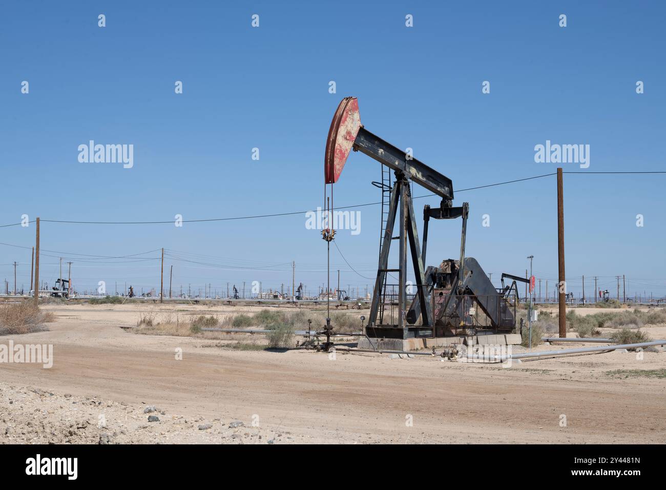 Oil derrick pumping in a dry barren central California oil field Stock ...