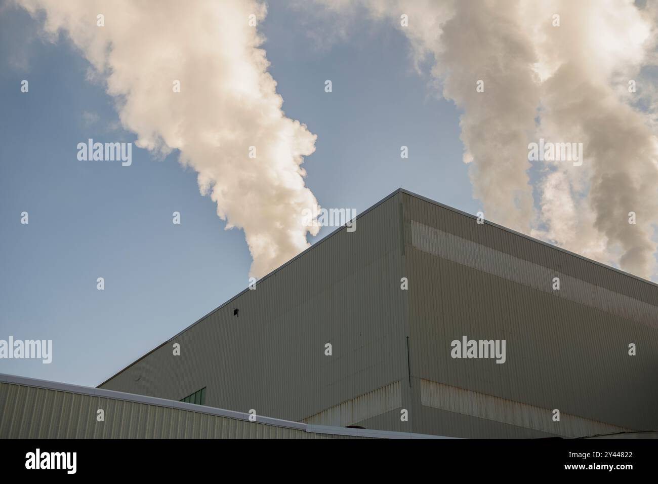 Steam smoke rising out of pale green box shaped industrial building ...