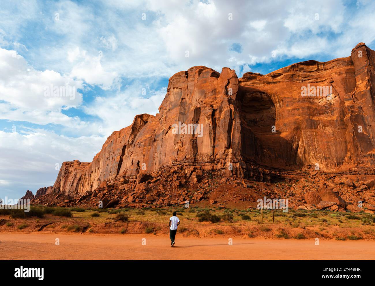 Man walking toward towering Rain God Mesa cliffs in Monument Valley ...