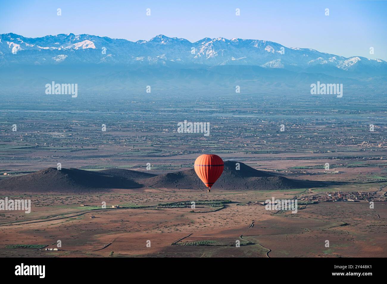 A red, hot air balloon, floating over the desert near Marrakech ...