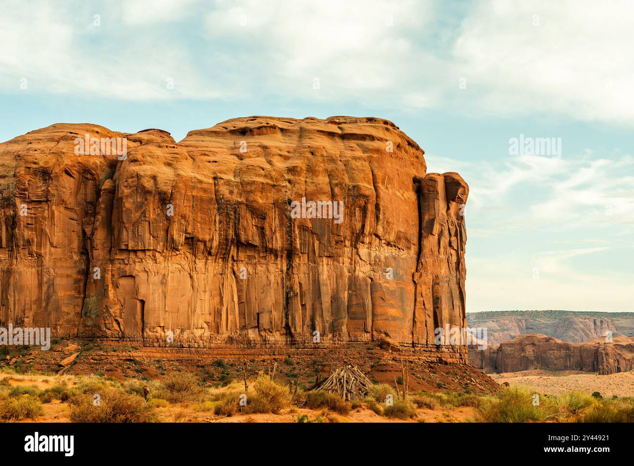 Sunlit sandstone cliffs rise in Monument Valleyâ€™s desert landscape ...