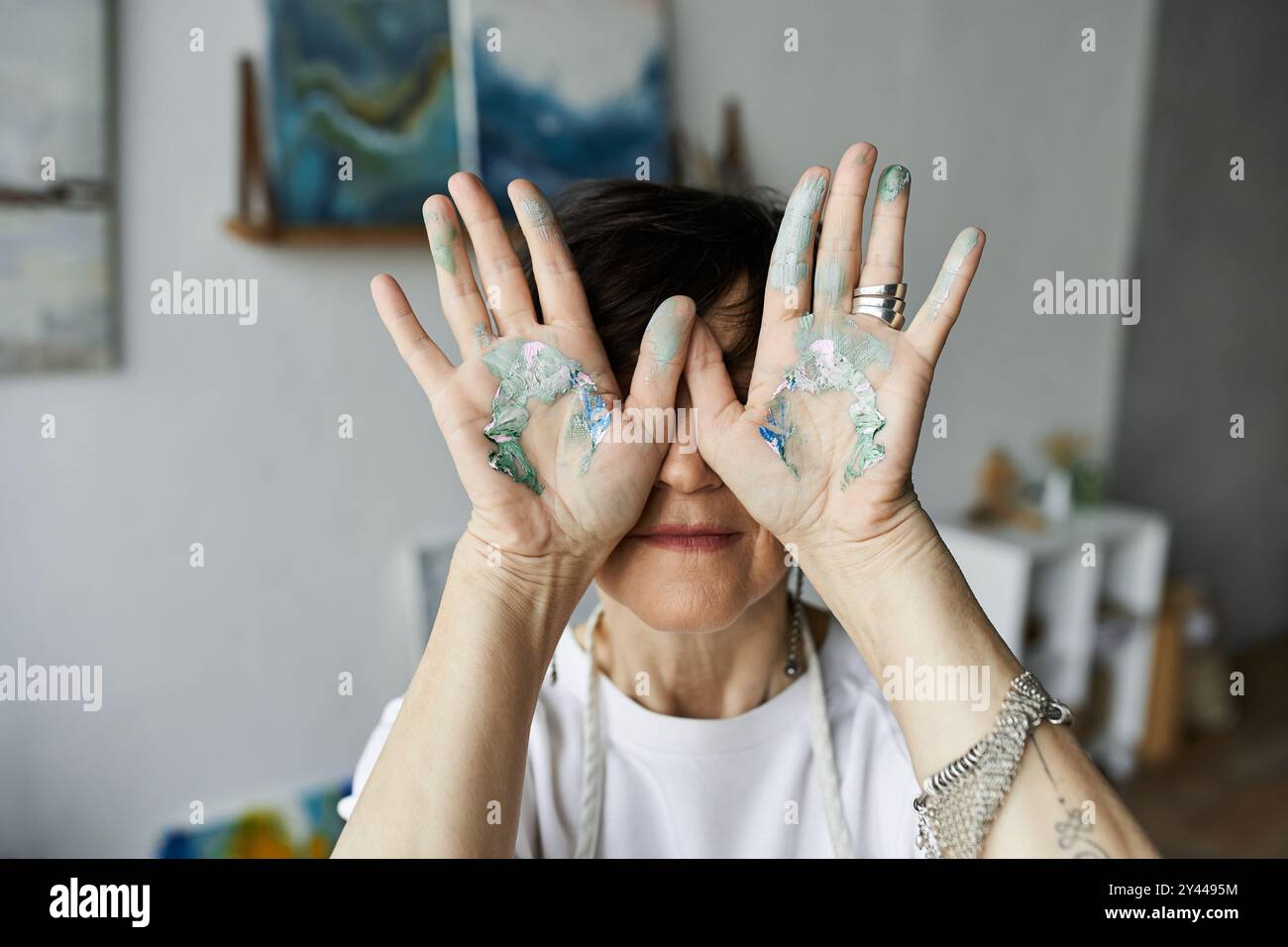 A woman playfully displays her paint stained hands while enjoying her ...