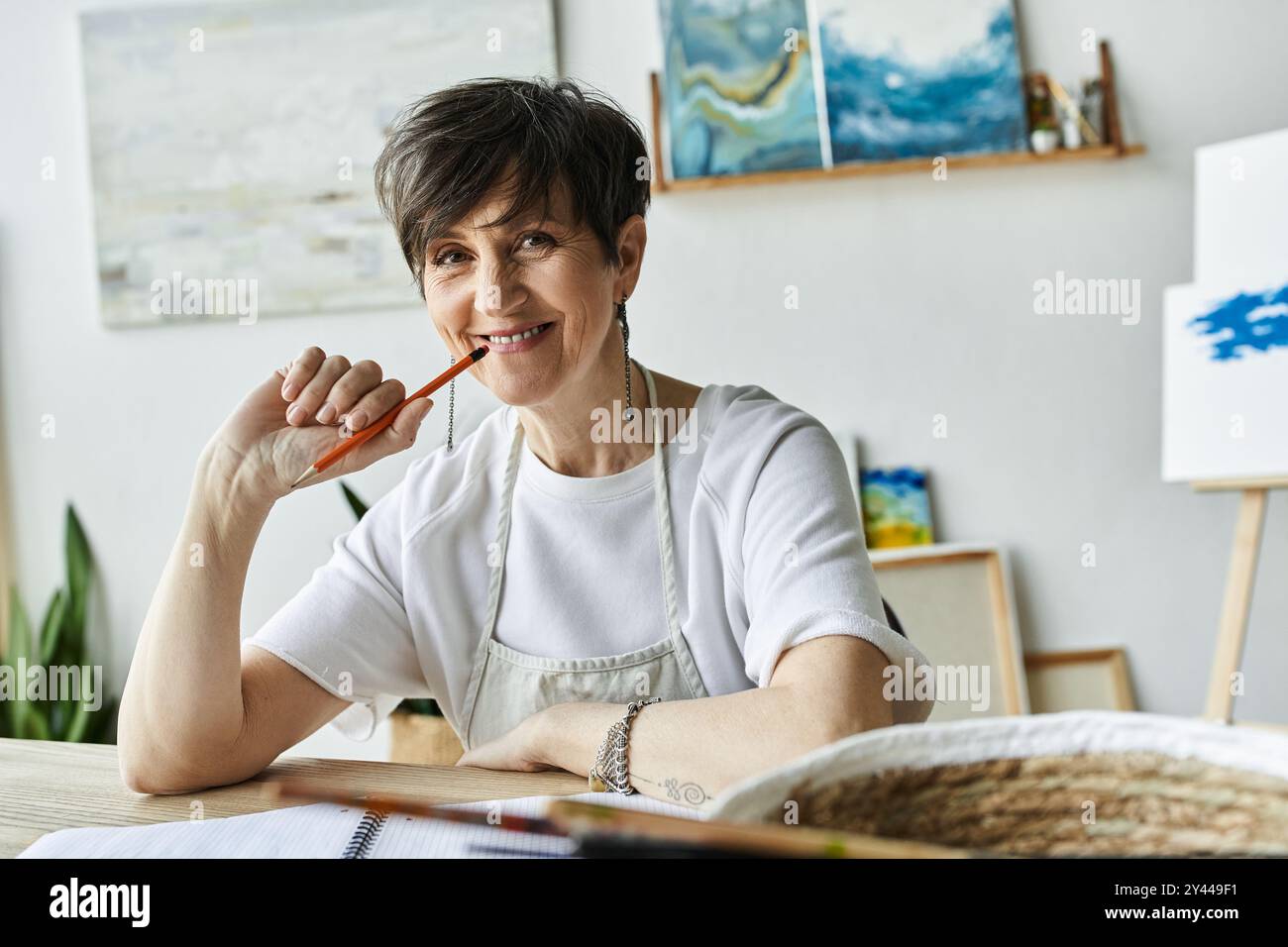 A painter smiles thoughtfully while taking a break in her vibrant art ...