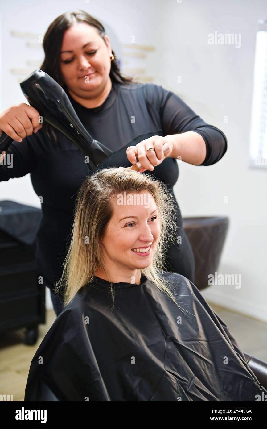 Woman smiling during hair styling session at a salon Stock Photo - Alamy