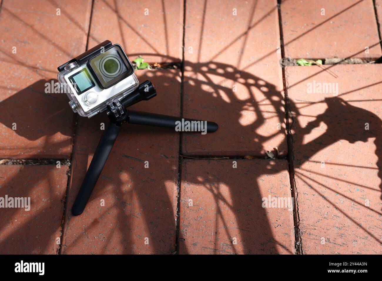 Modern action camera with tripod on pavement outdoors, above view ...