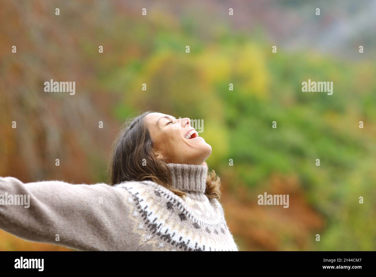 Happy middle aged woman outstretching arms outdoors in nature in autumn ...