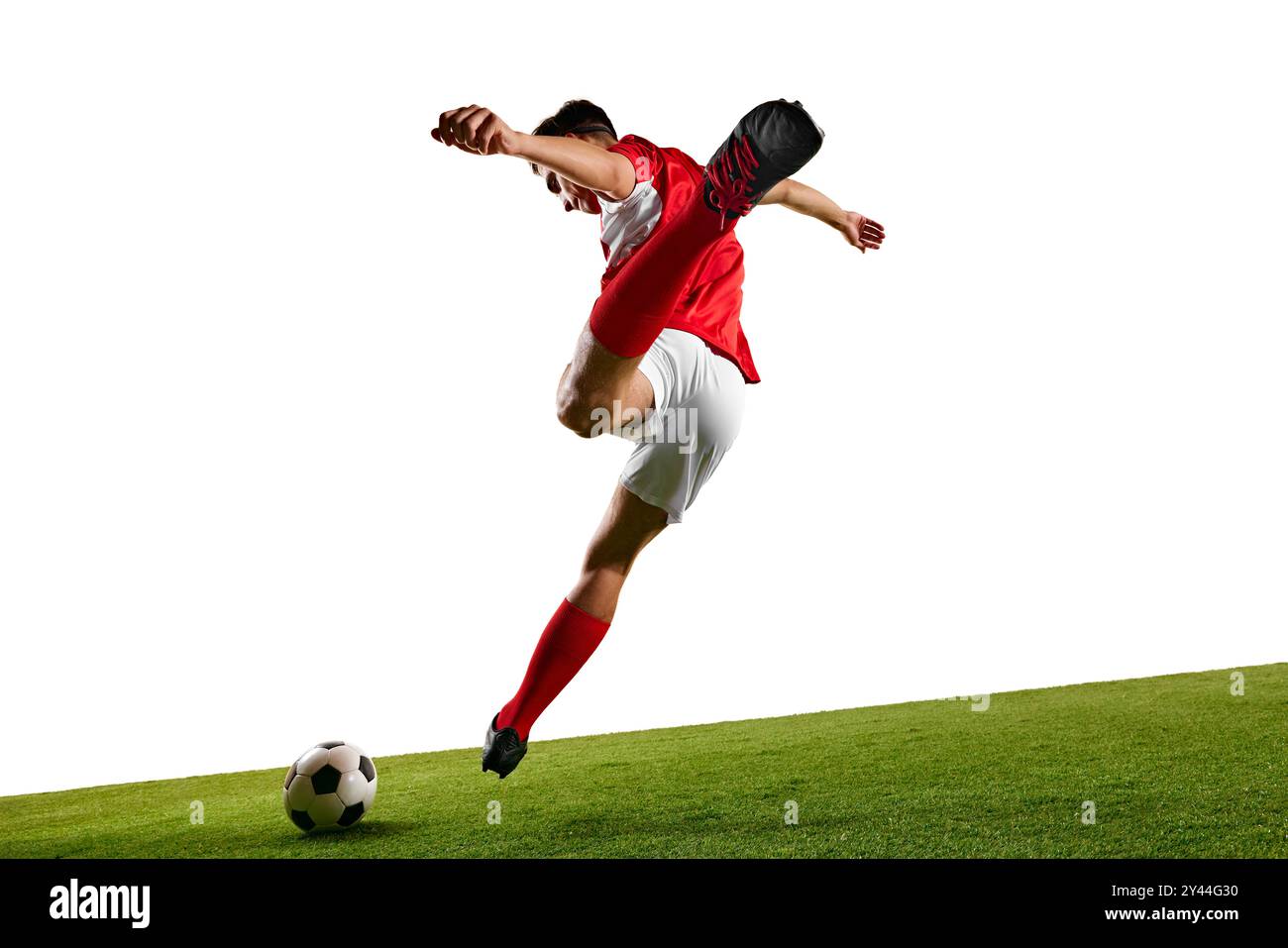 Footballer in red-white uniform, mid-jump while aiming strong kick ...
