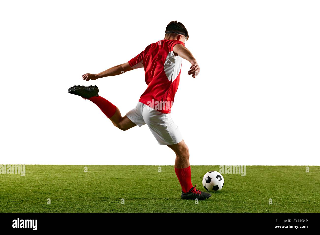 Determined football player in red-white, launching into jump-kick while ...