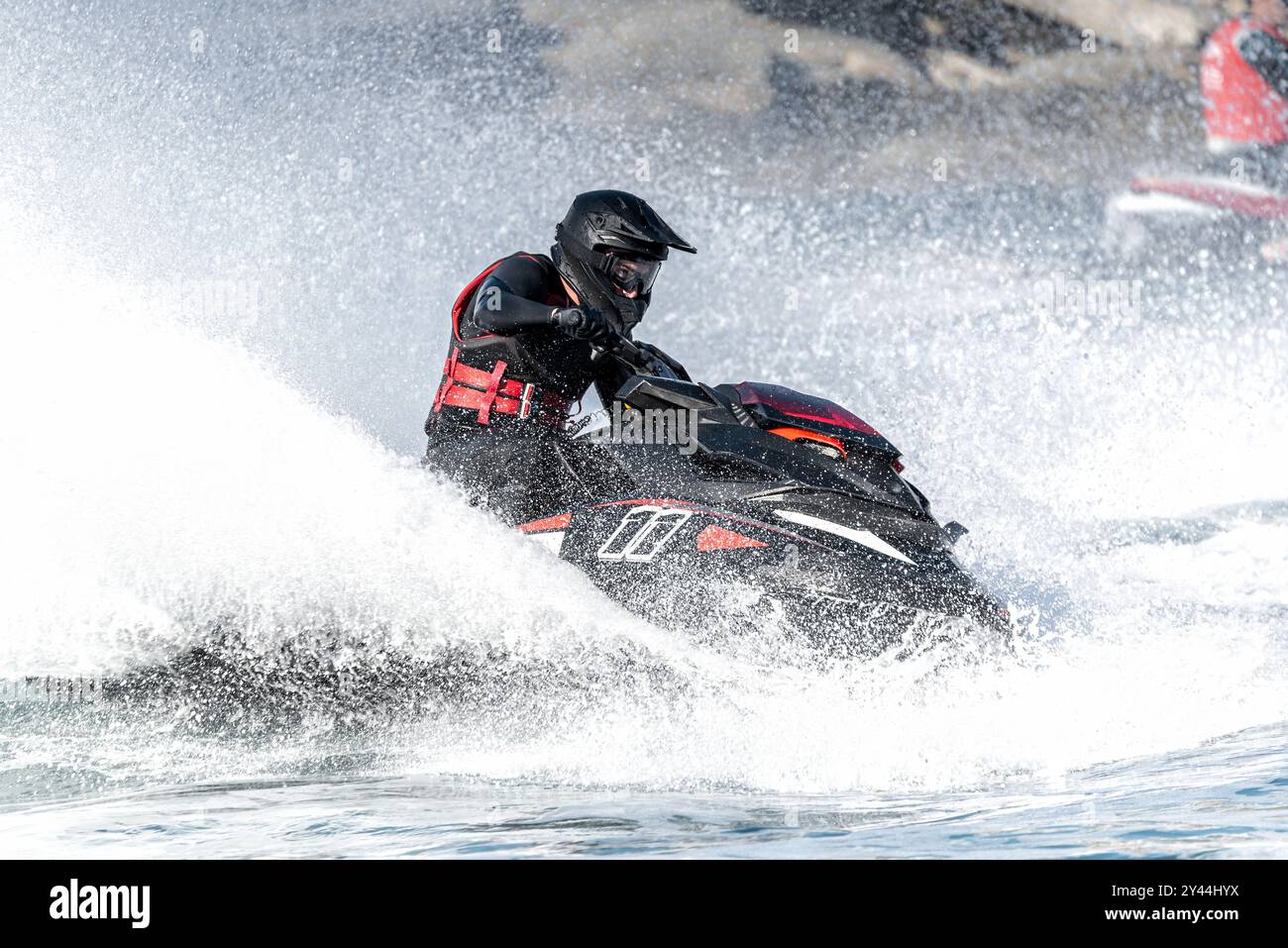 Professional athlete is riding a jet ski at high speed, creating a large splash Stock Photo - Alamy