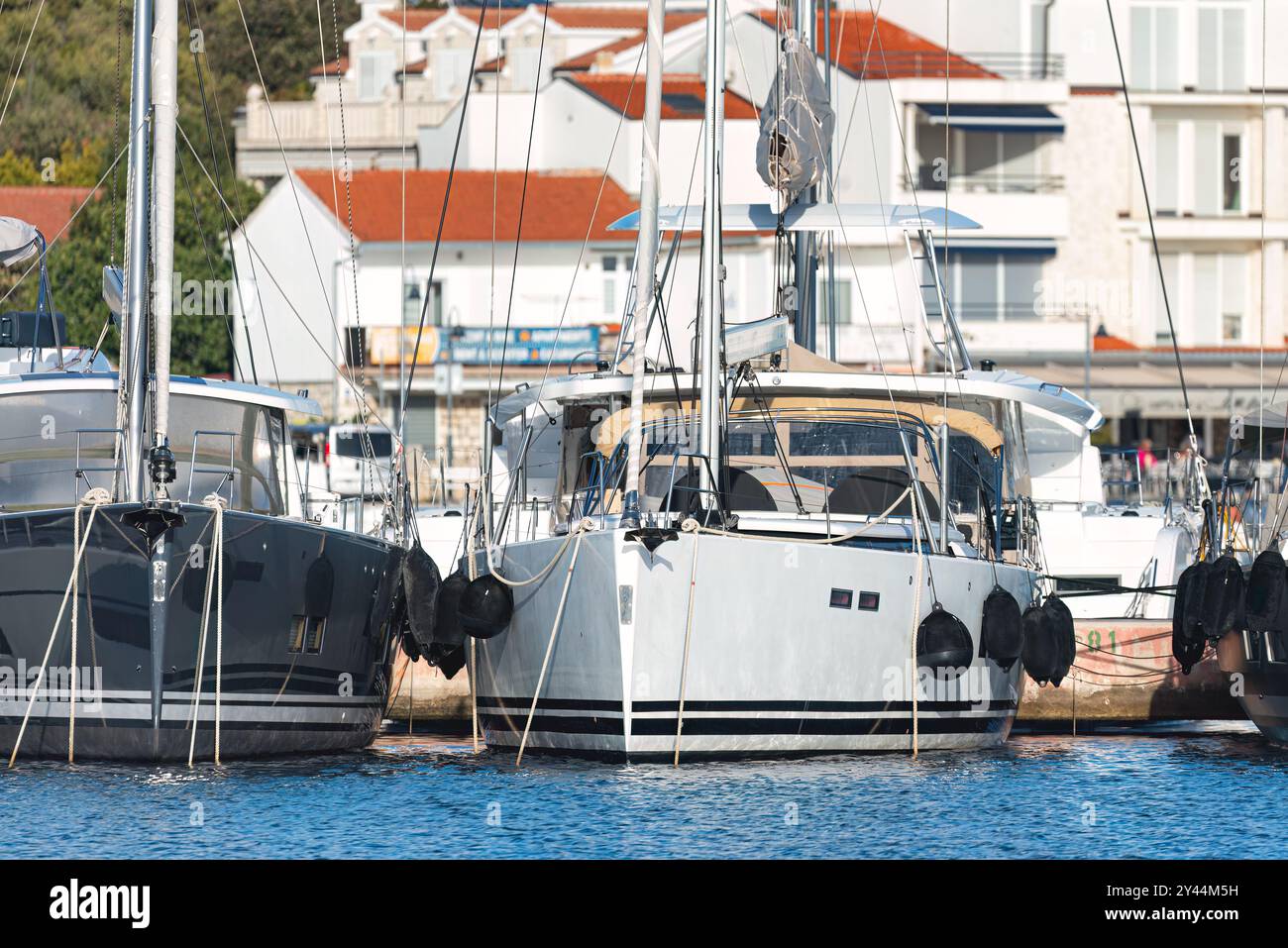 Modern sailboats with rolled-up sails are peacefully floating in the ...