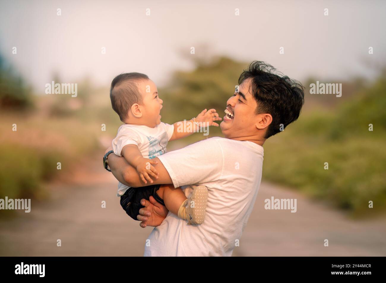 Dad smiled warmly at the baby boy as he lifted the baby boy. father ...
