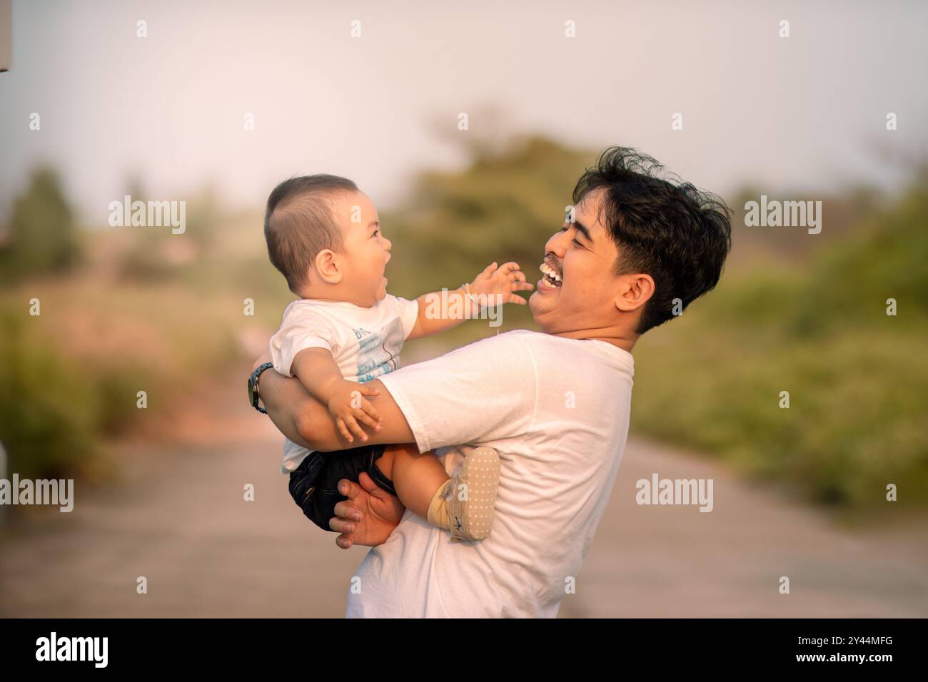 The father laughed out loud at the baby boy while lifting the baby boy ...