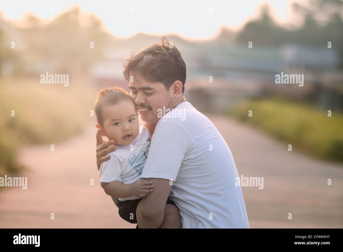 father holds and holds the baby boy's head tightly. baby boy makes an ...