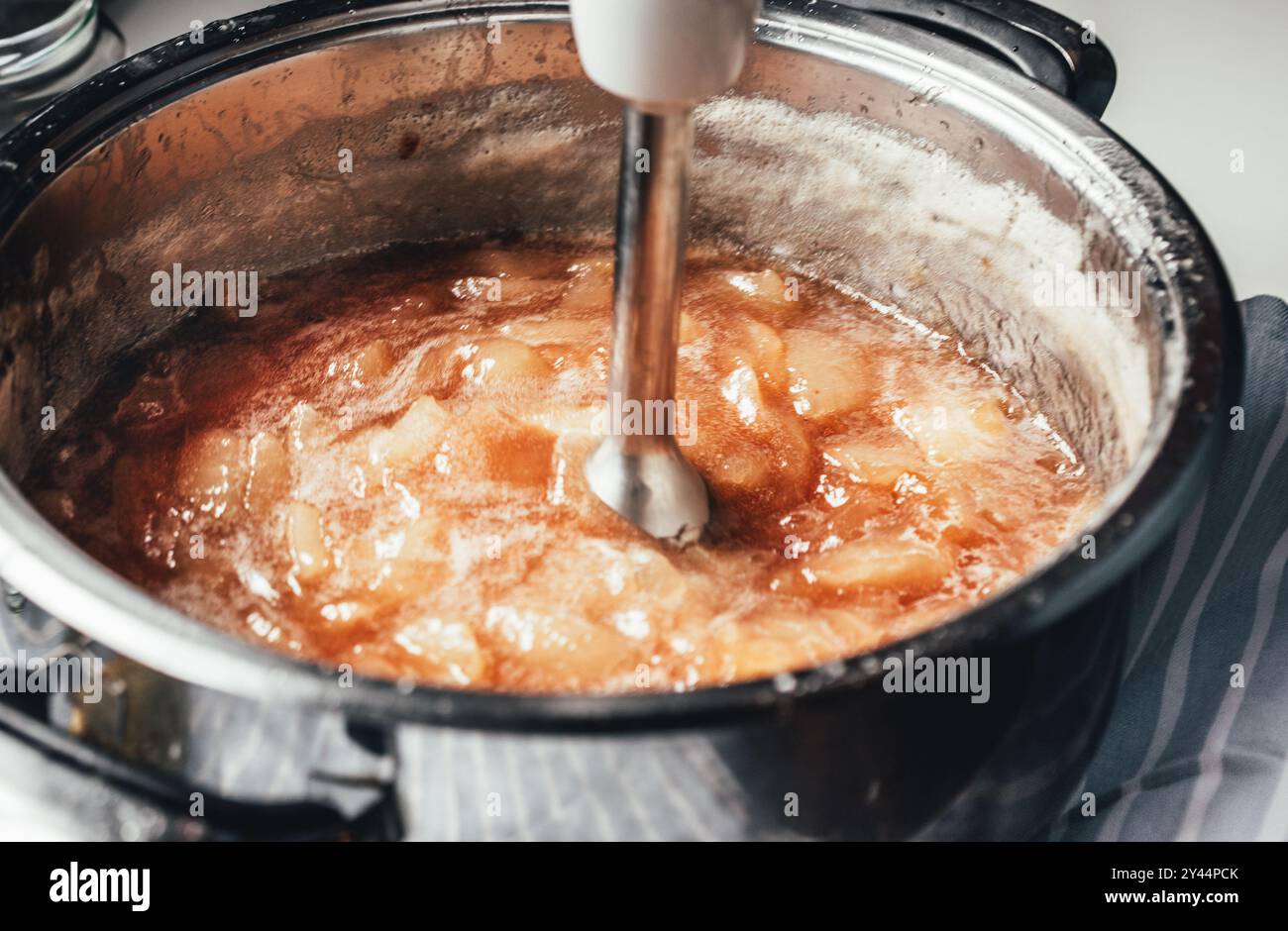 Blending homemade pear jam in a pot using an immersion blender, showing ...