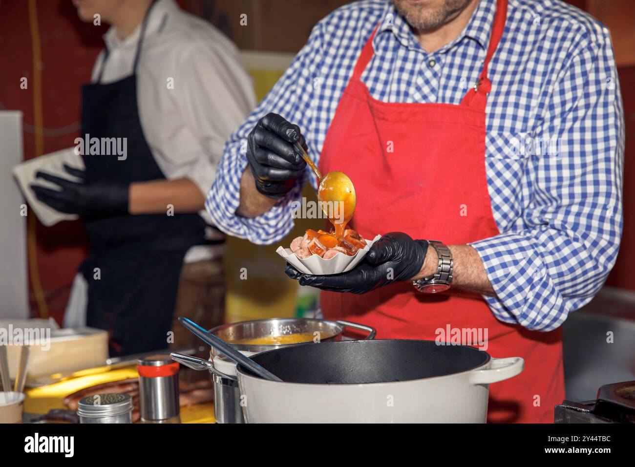 Chef preparing street food, a man wearing an apron, cooking at a food ...